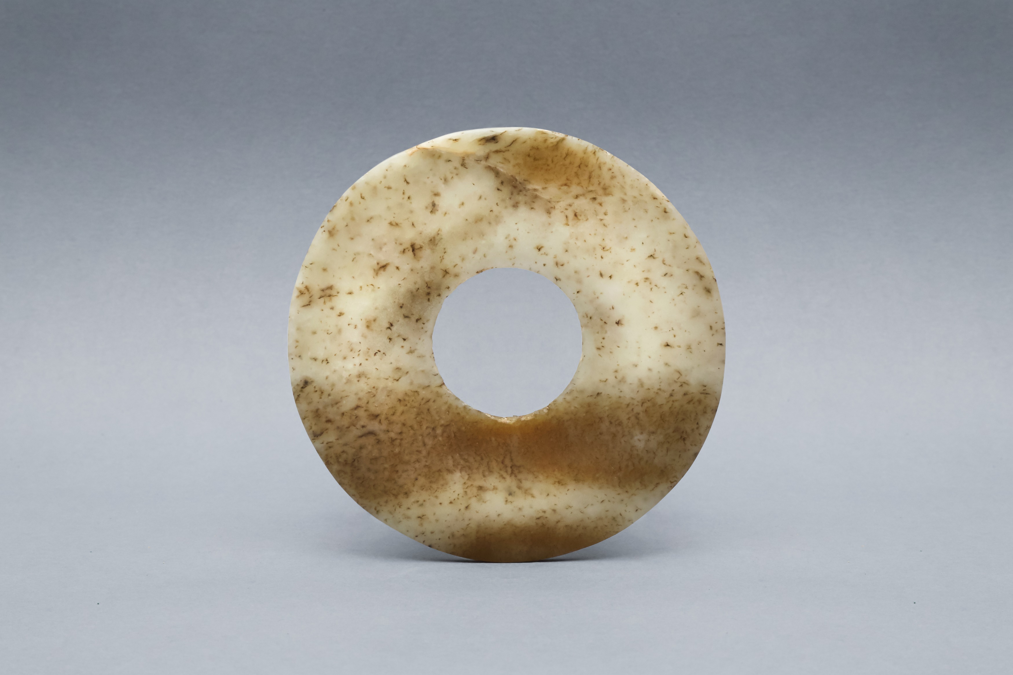 Lot 360 - A SMALL CHINESE ARCHAIC MOTTLED JADE DISC,